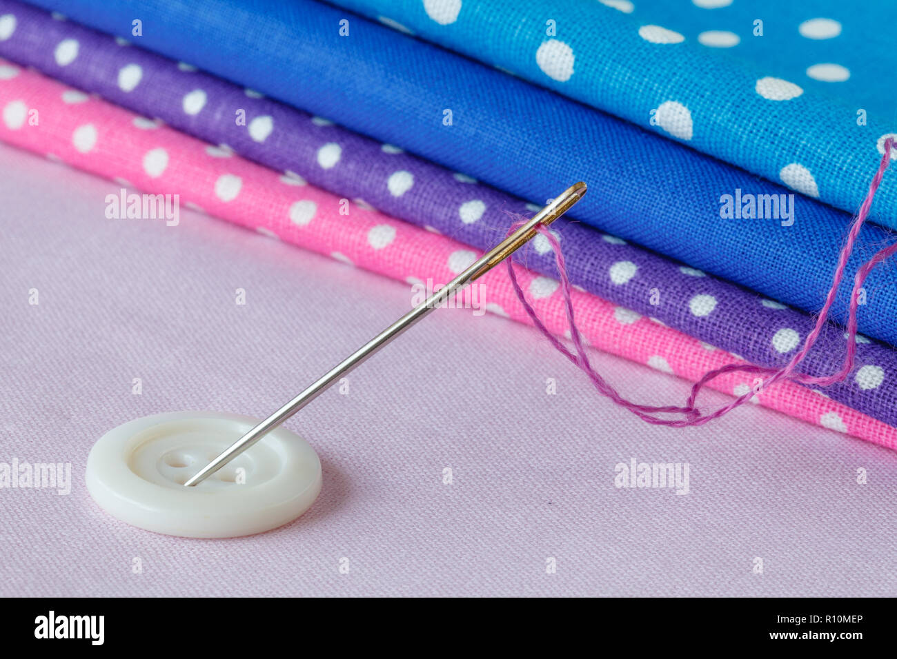 Close up of a button with needle and thread Stock Photo - Alamy