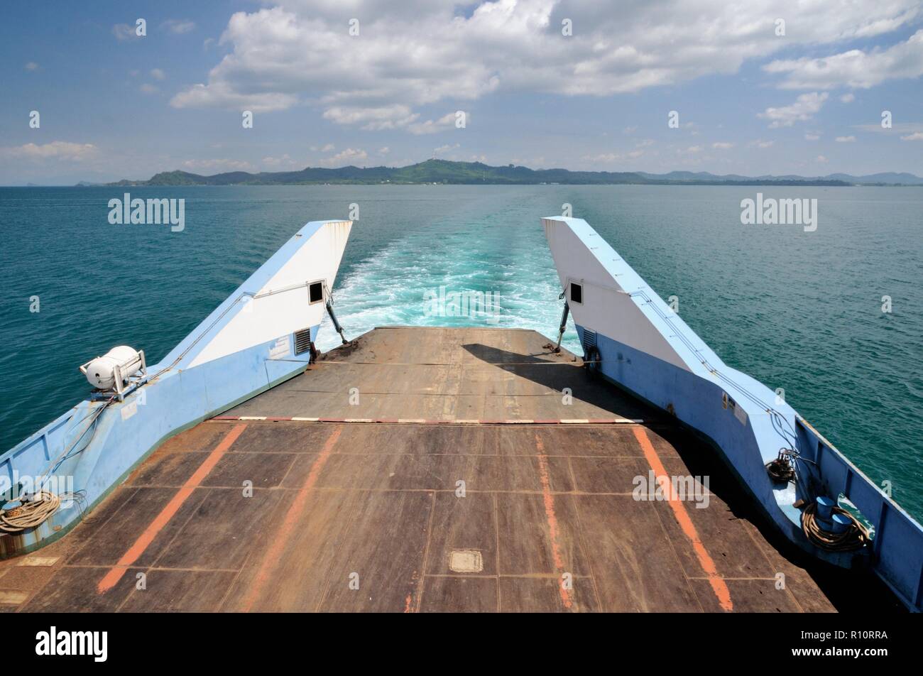 Ferry ramp, ferry deck and trace on the water of tropical sea behind ...
