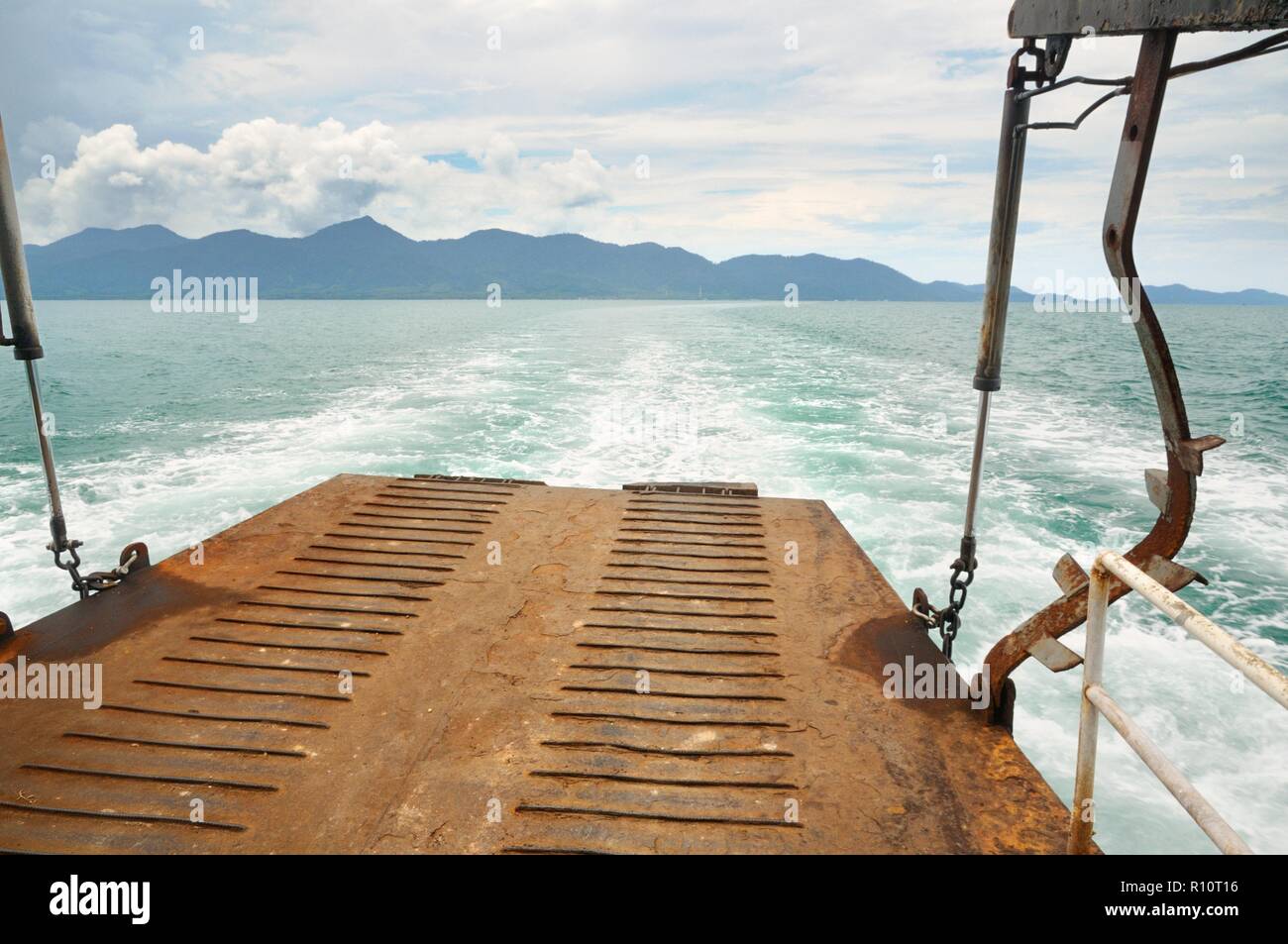Ferry ramp and trace on the water of tropical sea behind ferry, with ...