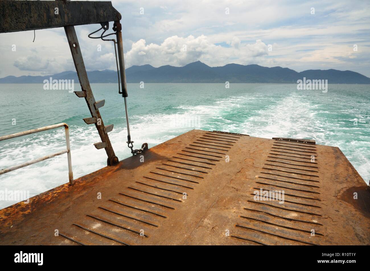 Ferry ramp and trace on the water of tropical sea behind ferry, with ...