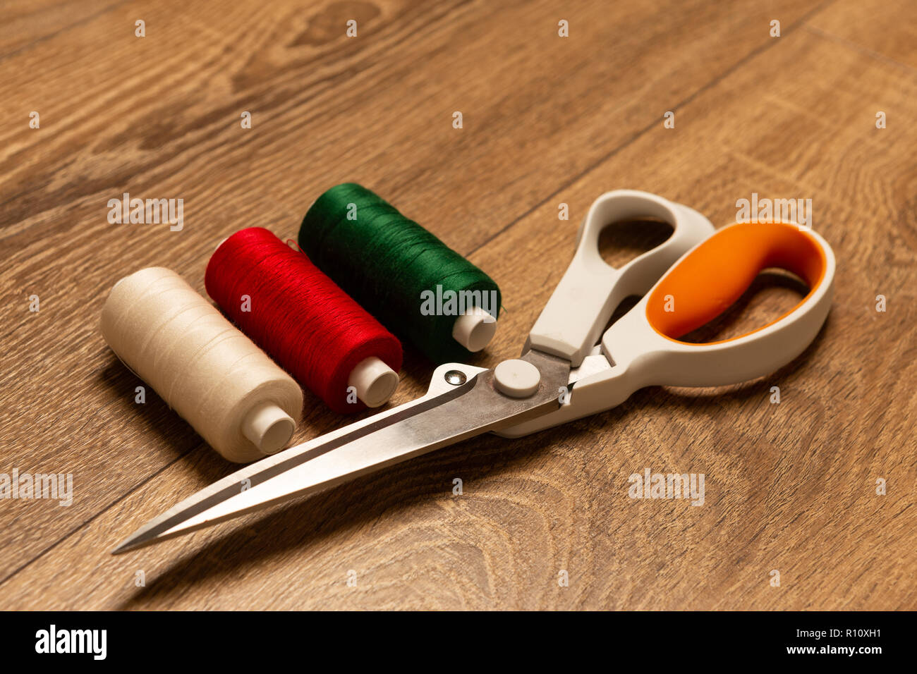 Coulourful red white green thread spools and pair of scissors on wooden ...
