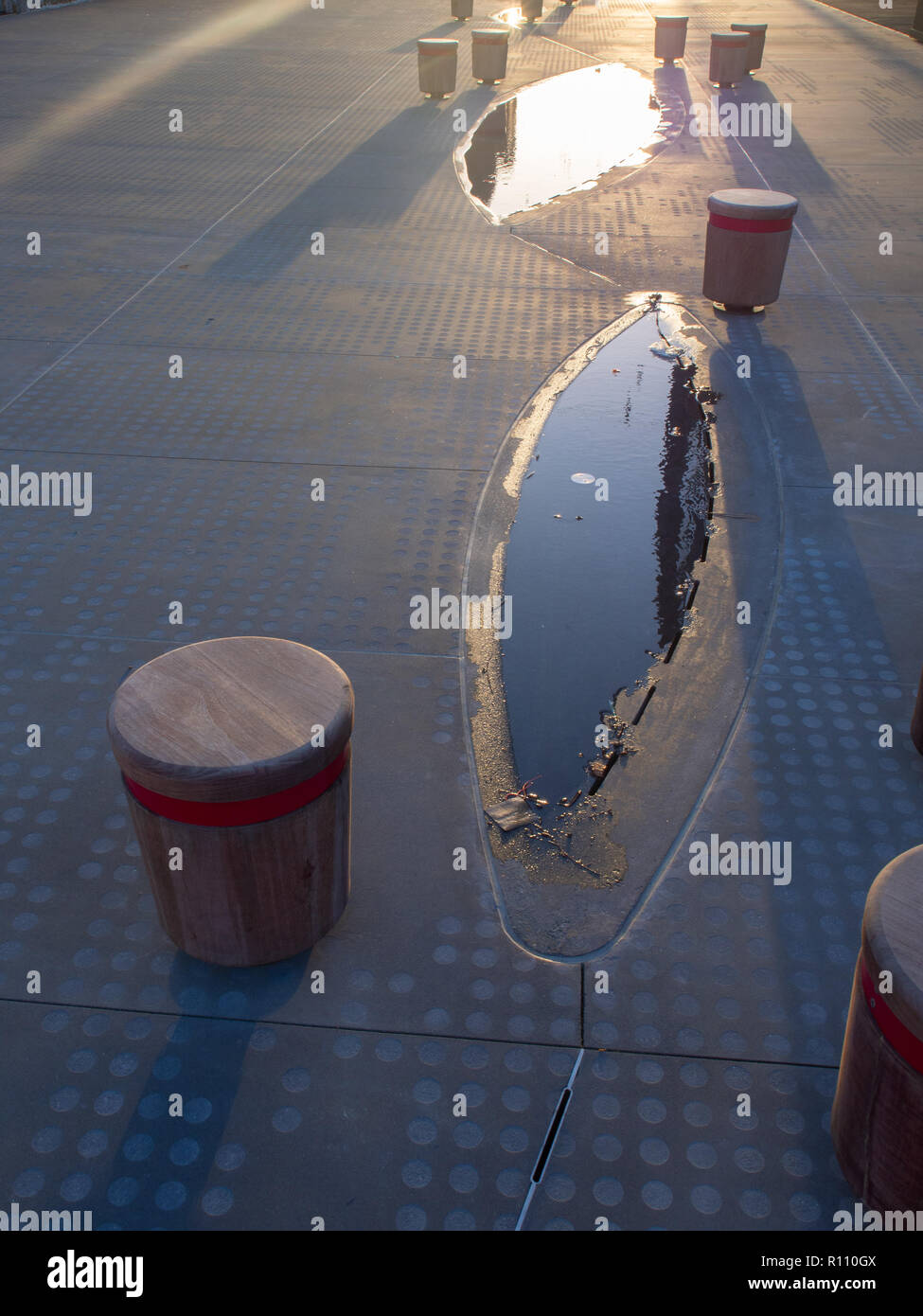 Round Seats And Puddles On The Pavement Stock Photo - Alamy