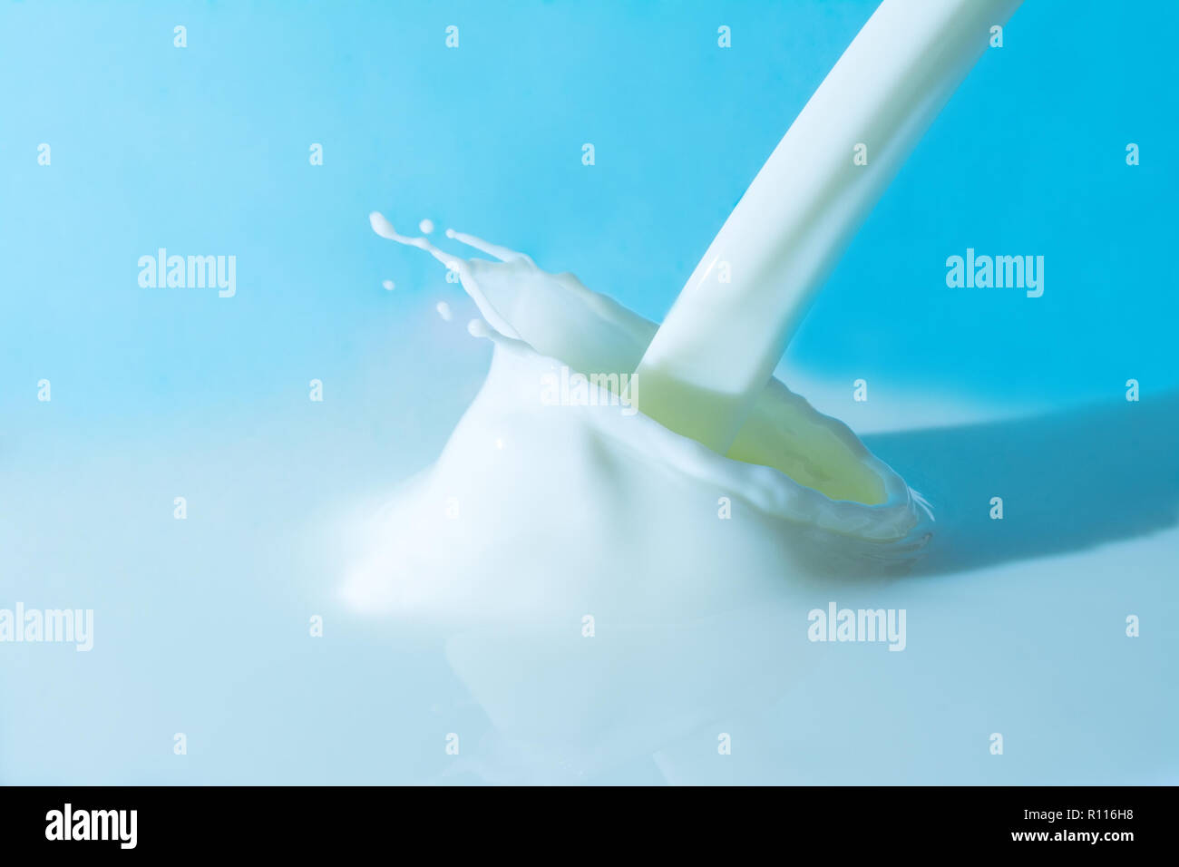 Splash of milk, pouring jet stream of milk on a light blue background ...
