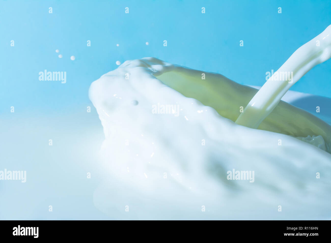 Splash of milk, pouring jet stream of milk on a light blue background ...