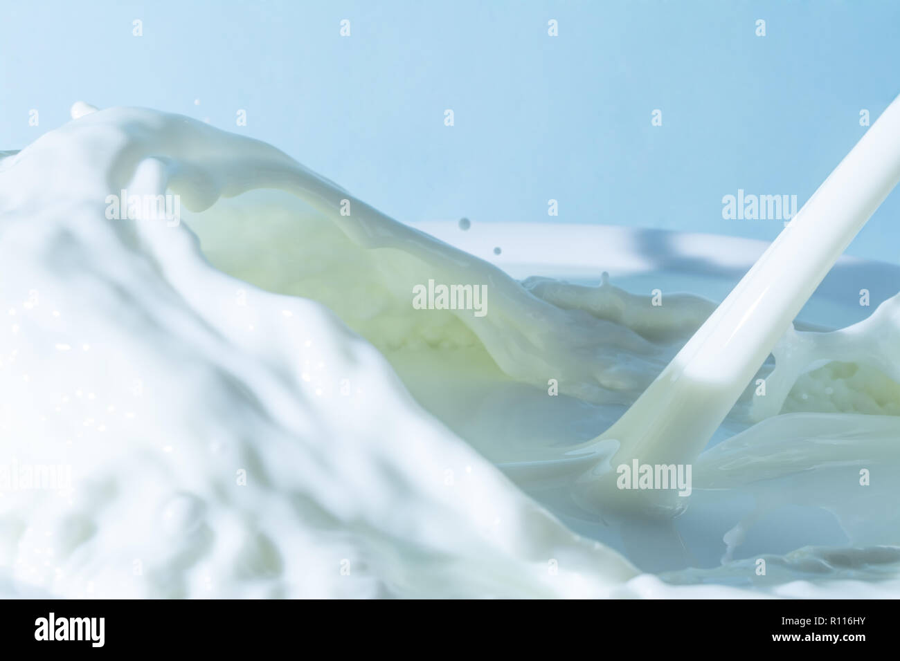 Splash of milk, pouring jet stream of milk on a light blue background ...
