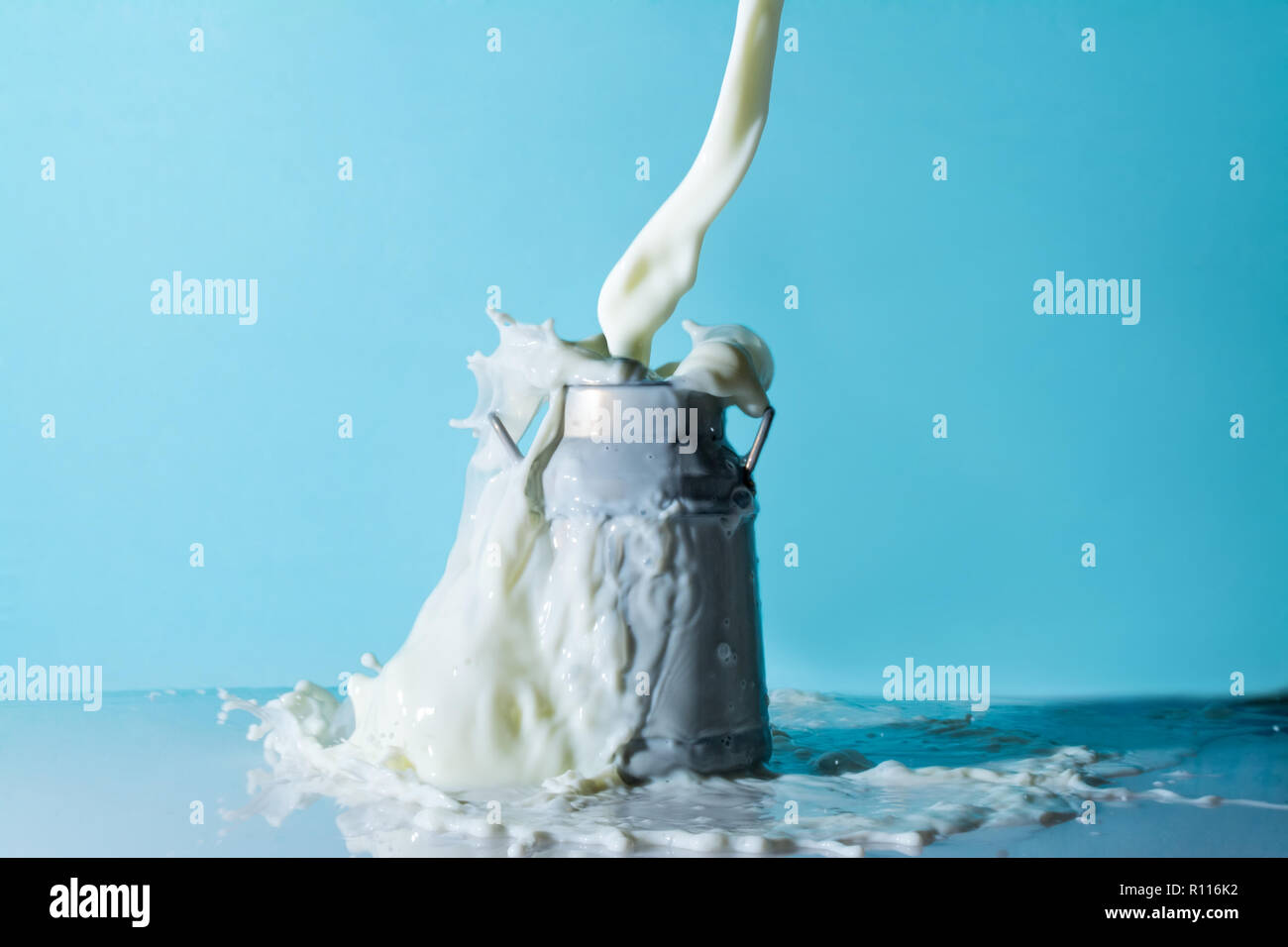 Splash of milk, stream of milk pouring into a overflowing can of milk ...