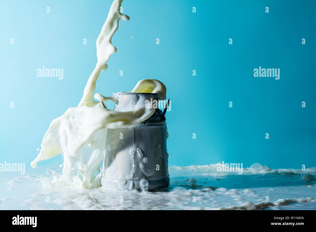 Splash of milk, stream of milk pouring into a overflowing can of milk ...