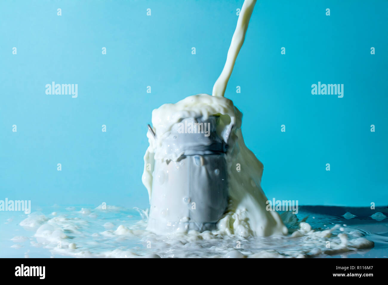 Splash of milk, stream of milk pouring into a overflowing can of milk ...