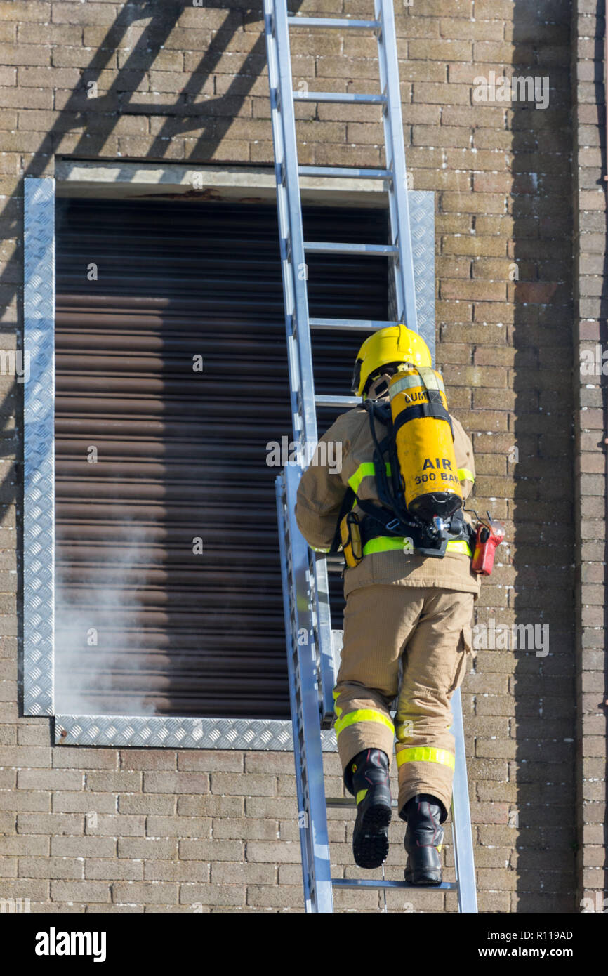 A firefighter using ladder access to enter a smoke filled tower during ...