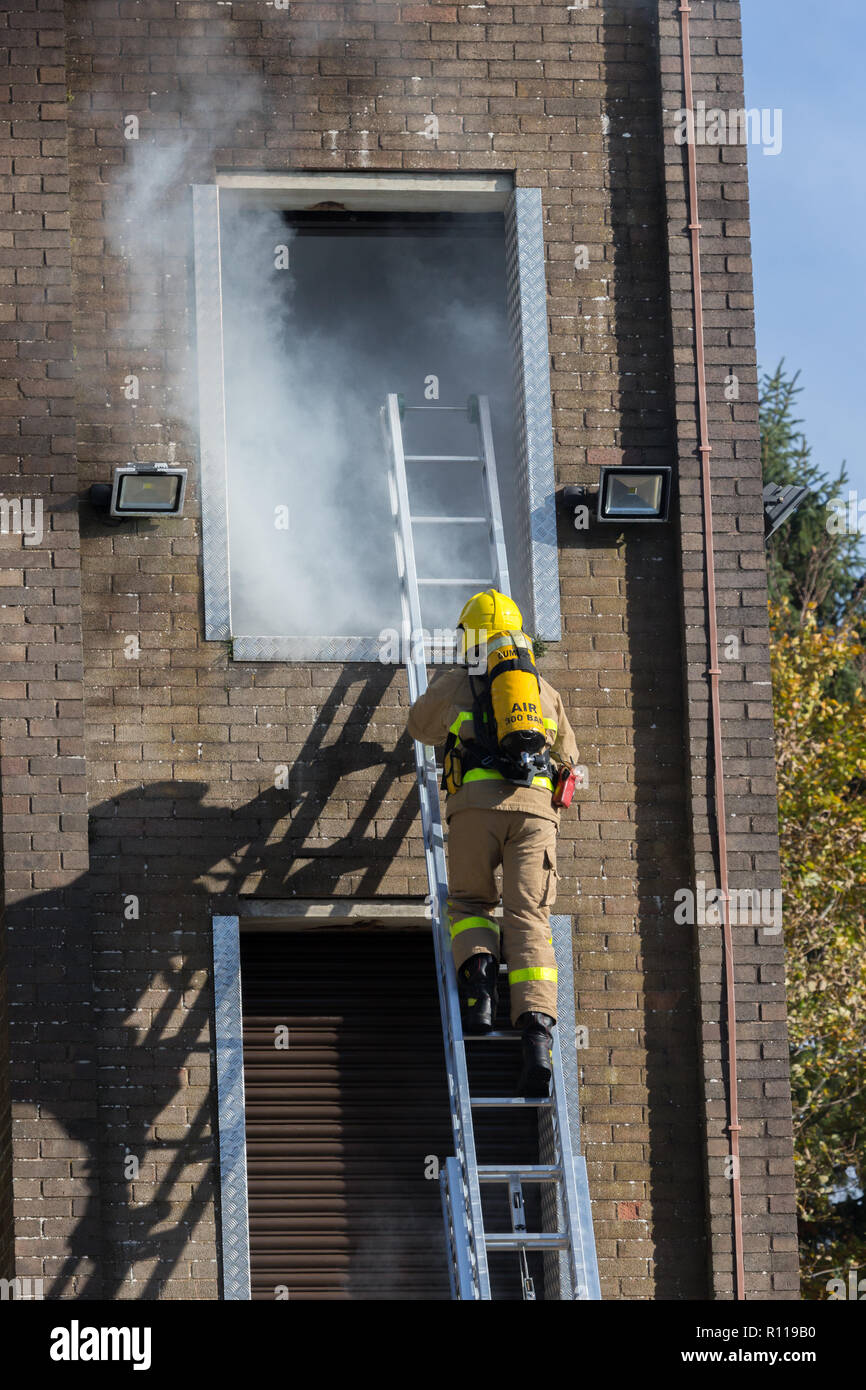 A firefighter using ladder access to enter a smoke filled tower during ...
