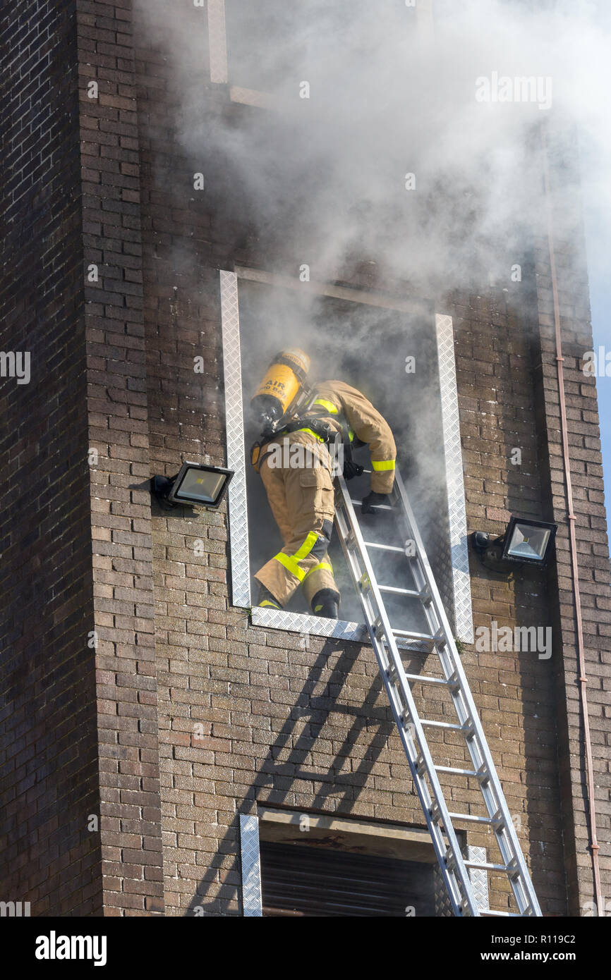 A firefighter using ladder access to enter a smoke filled tower during ...
