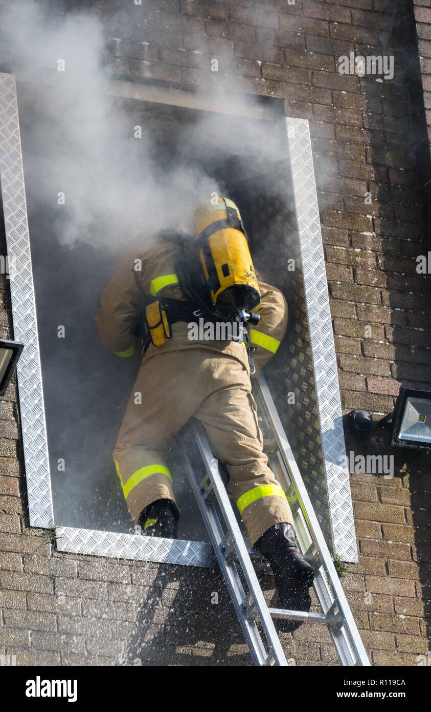 A firefighter using ladder access to enter a smoke filled tower during ...