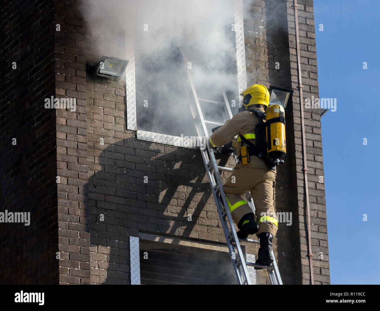 A firefighter using ladder access to enter a smoke filled tower during ...