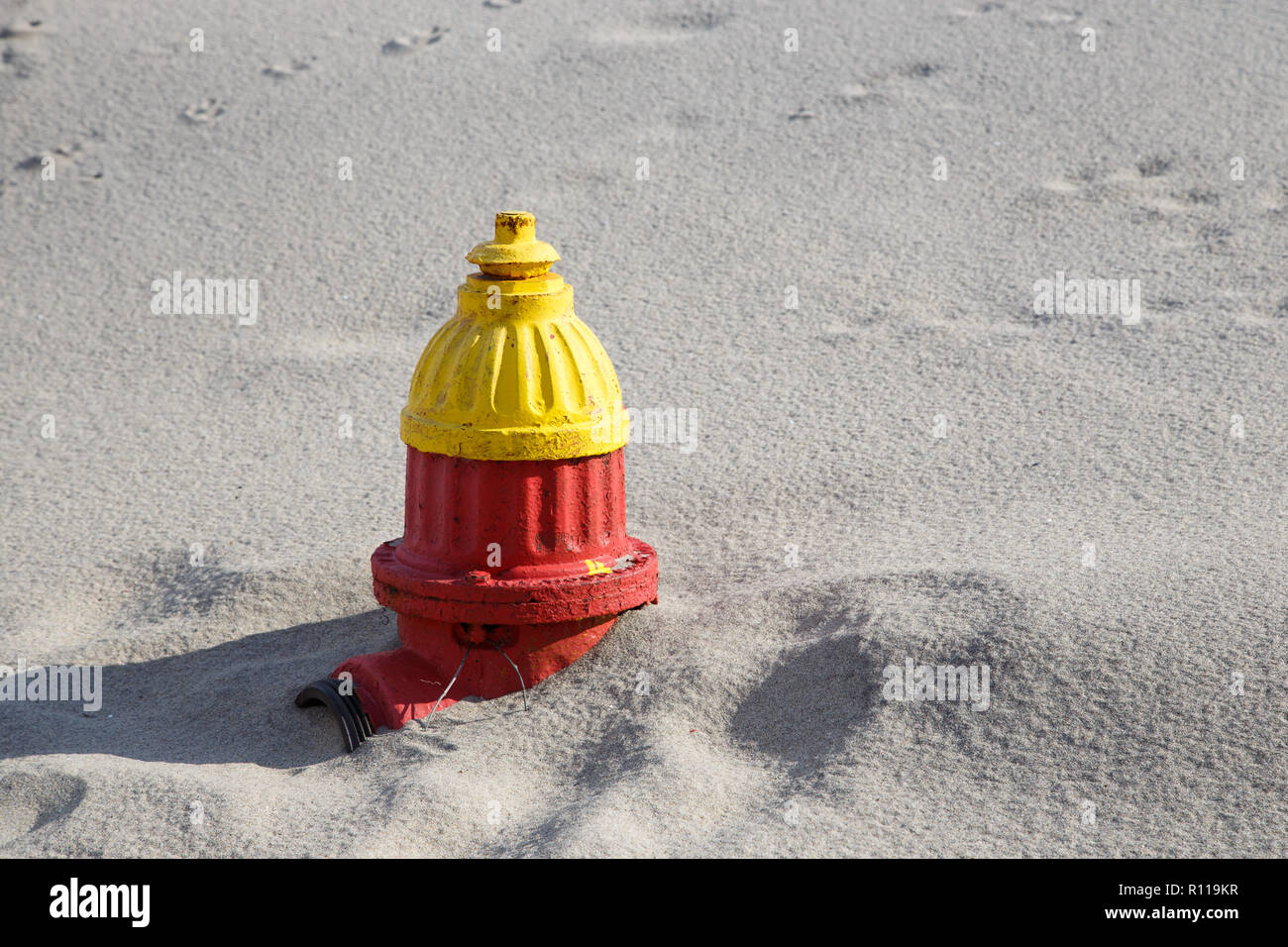 A colorful red-and-yellow fire hydrant buried in sand. Echoes of ...