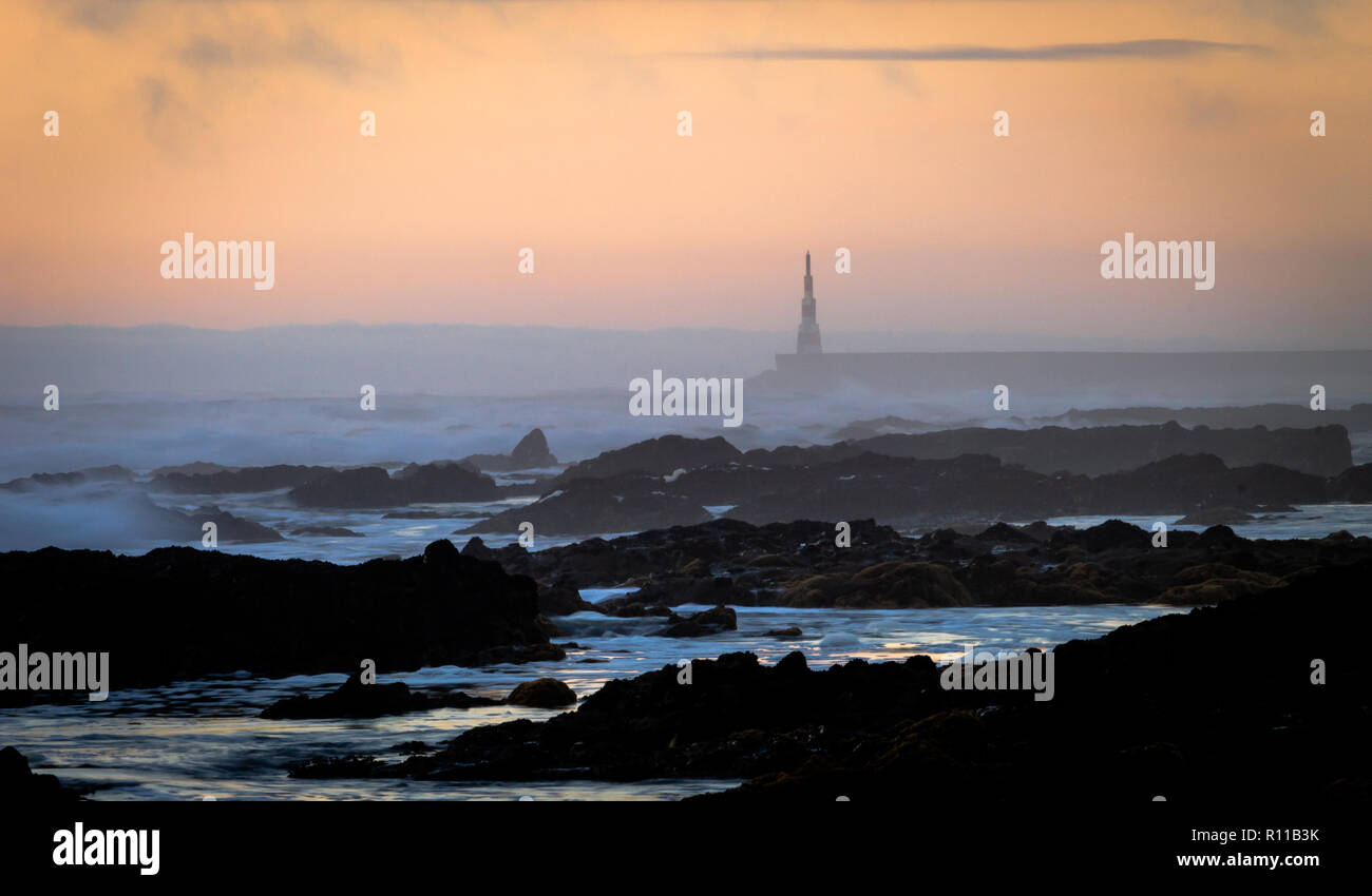 Seascape at sunset. Beacon, rocks, waves. Warm light Stock Photo - Alamy