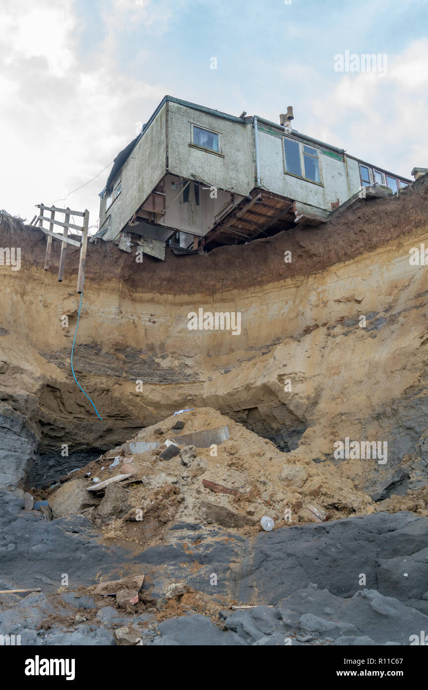 House on edge of cliff washed away by the sea, coastal erosion, global ...