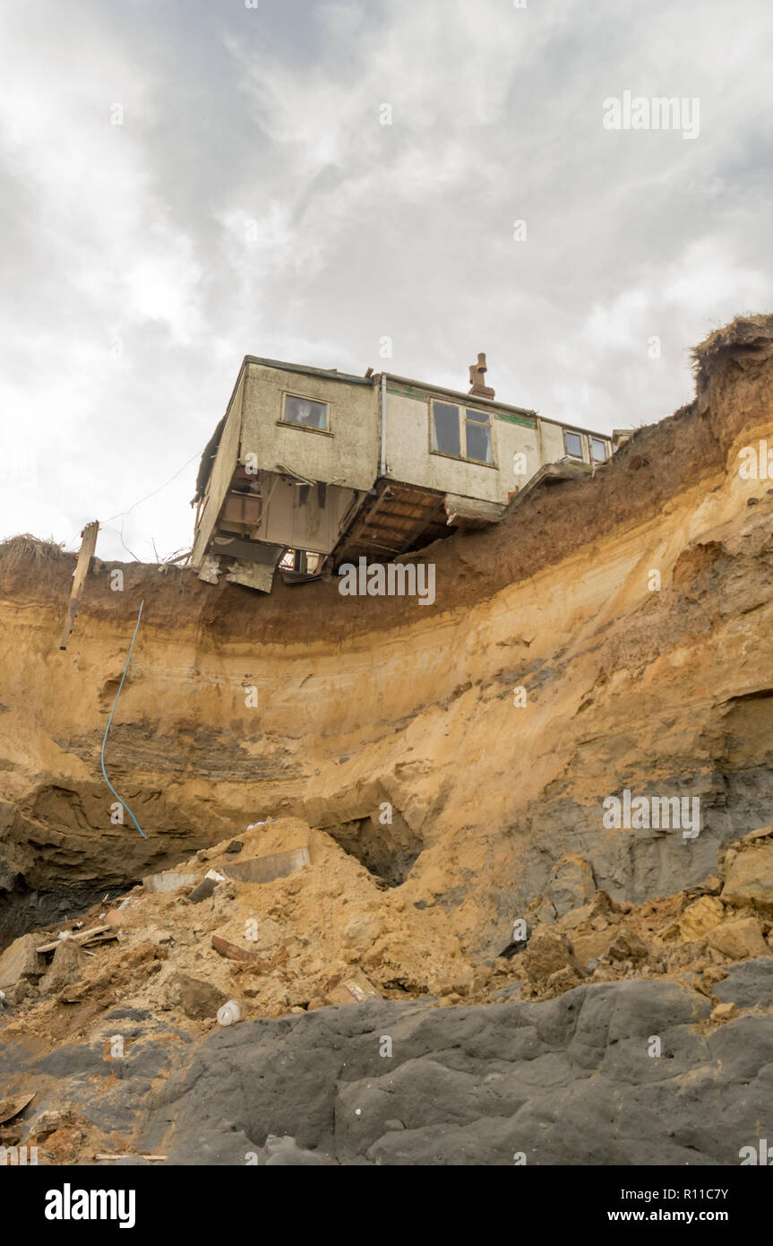 House on edge of cliff washed away by the sea, coastal erosion, global ...