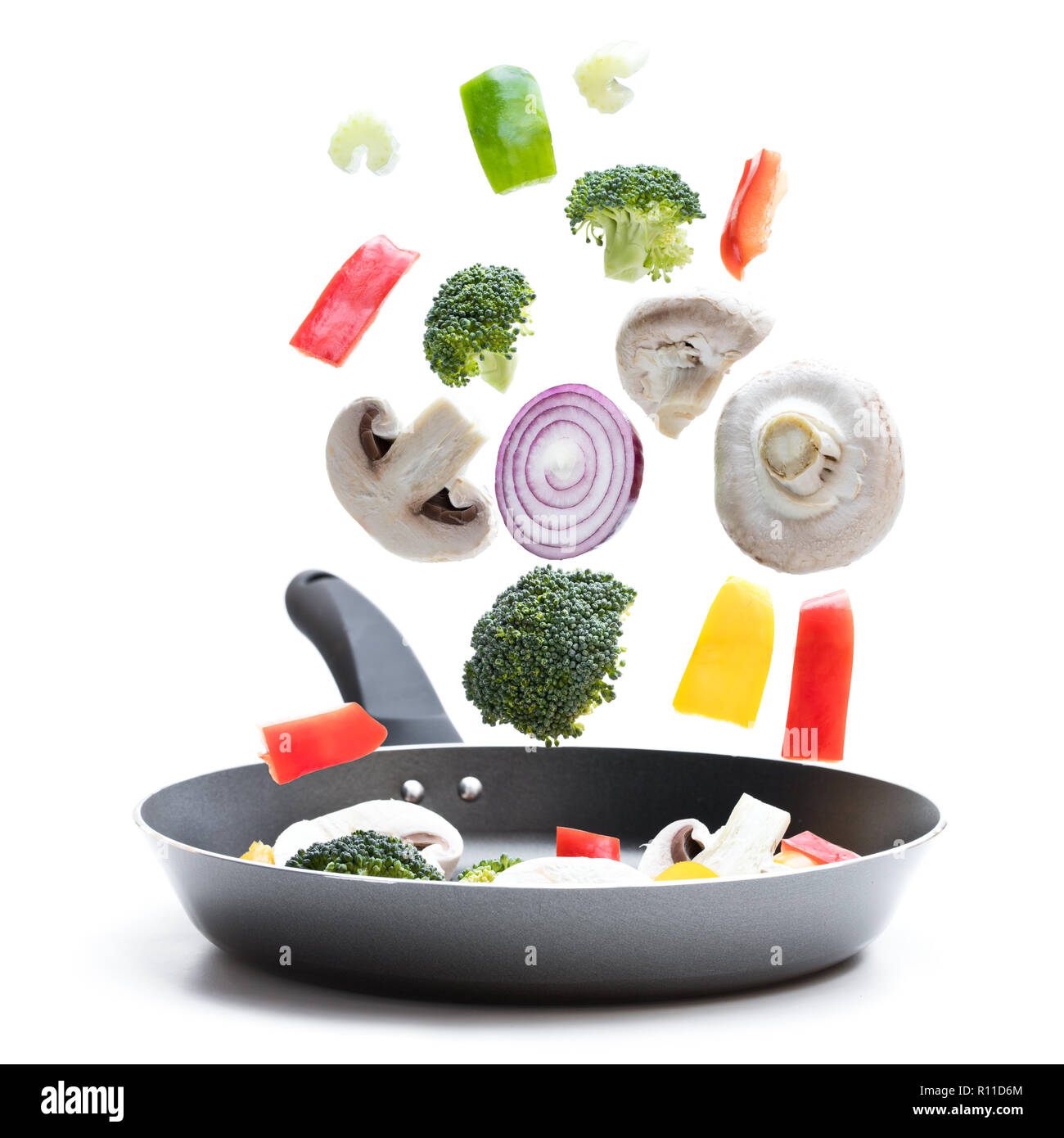 Fresh vegetables ready for cooking flying into a pan isolated on white ...