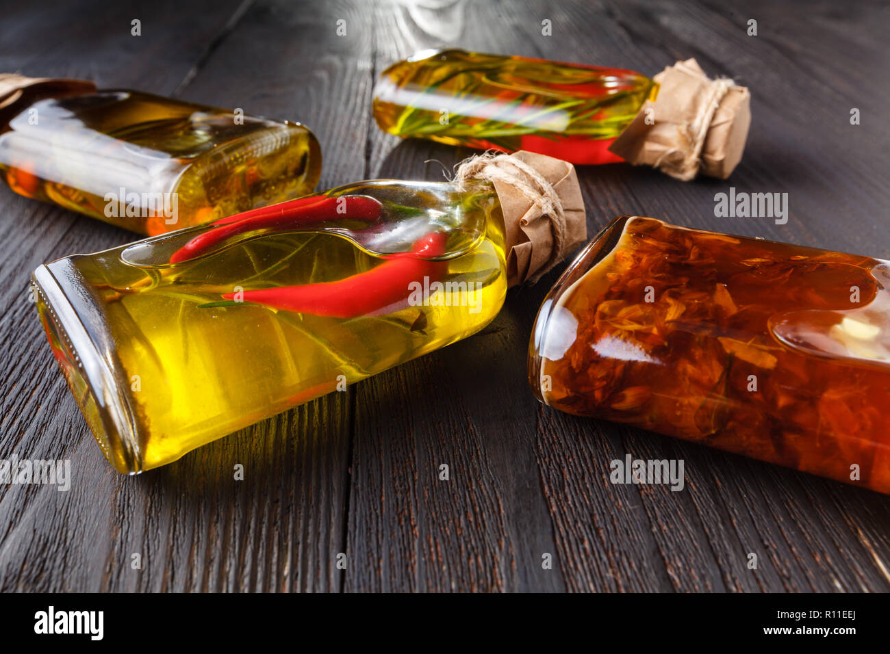 Assortment of spicy oils with herbs and spices in different bottles ...