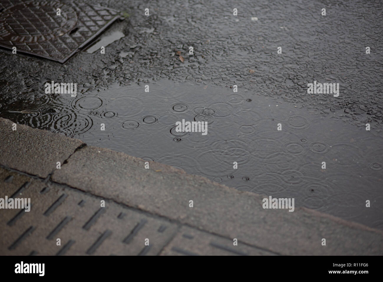Rain drops in a puddle by a pavement in St Andrews, Scotland Stock ...