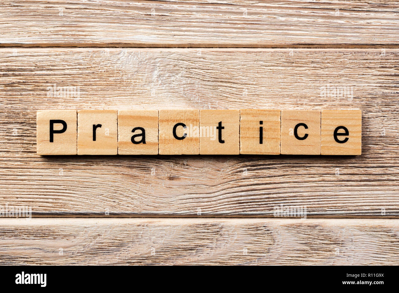 practice word written on wood block. practice text on table, concept ...