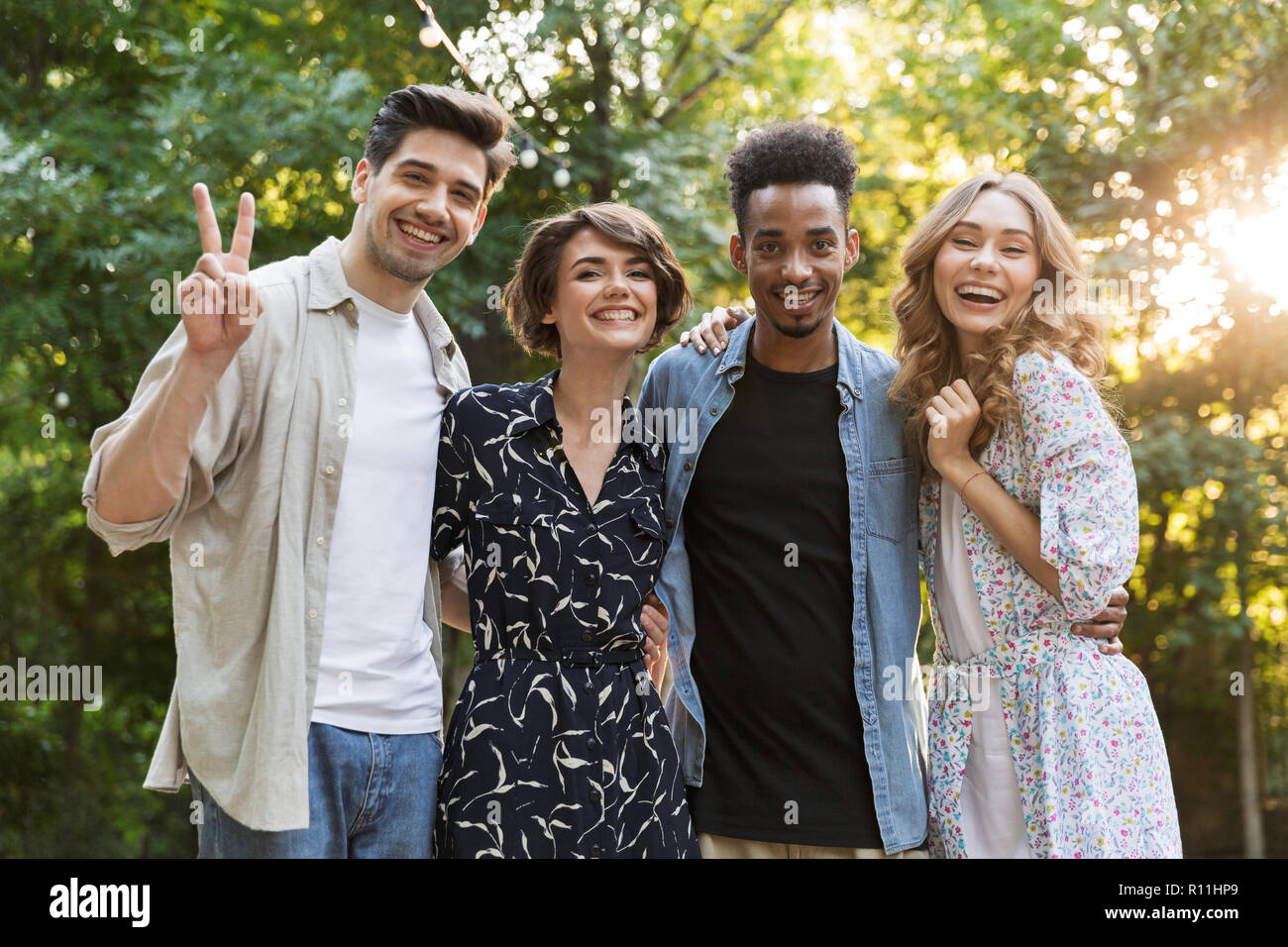 Group of four cheerful friends spending time together at the park ...