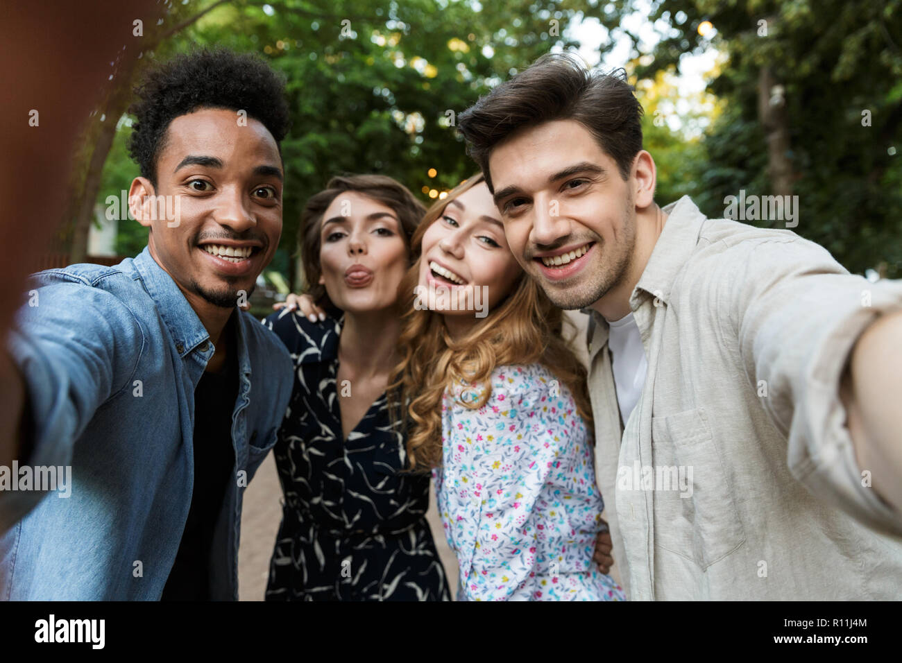 Image of happy young group of friends outdoors in park having fun take ...