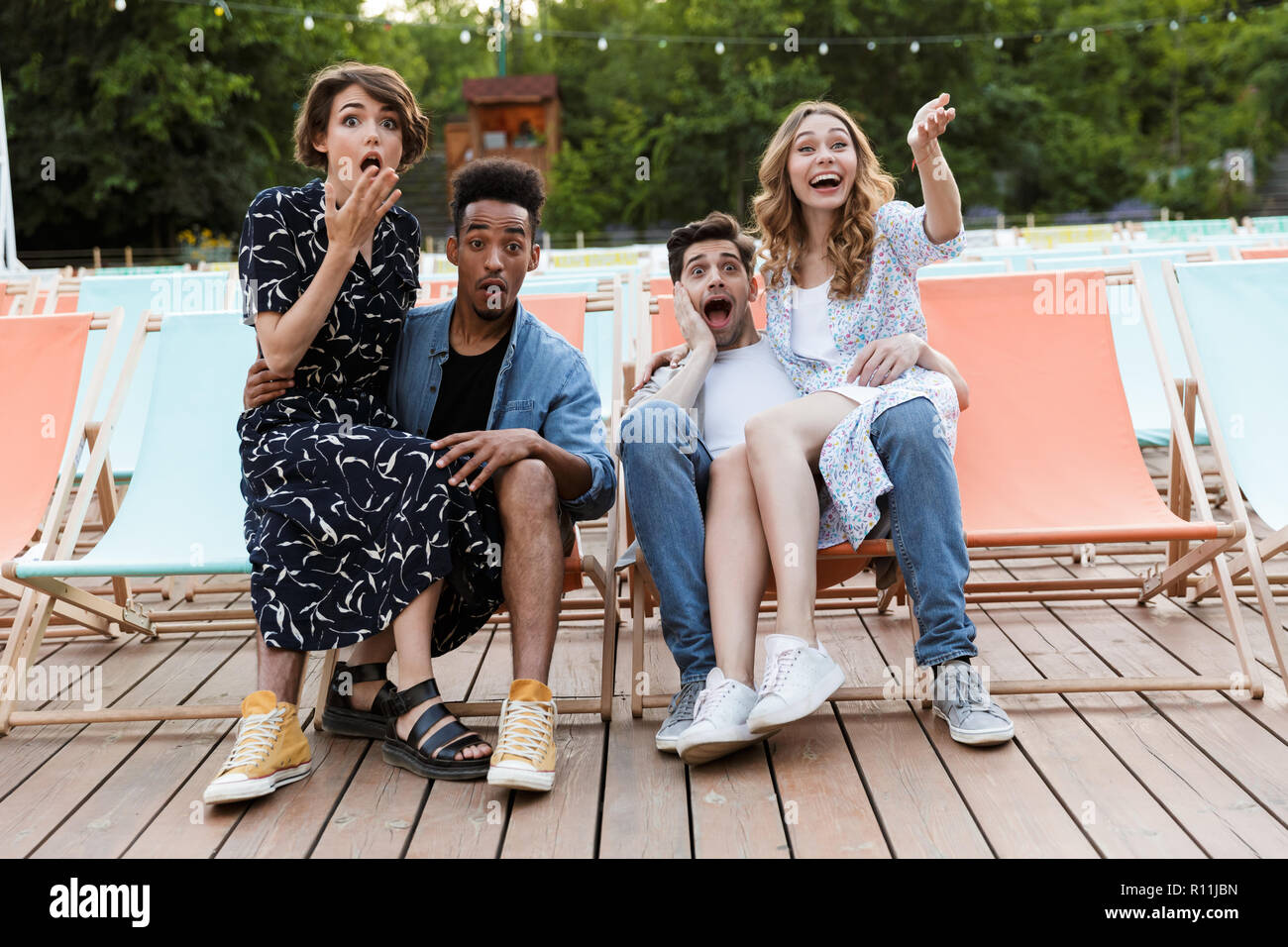 Image of shocked excited young group of friends sitting outdoors ...