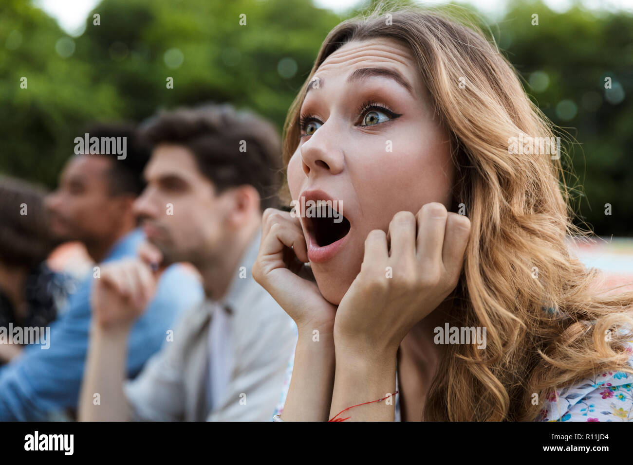 Image of shocked emotional young group of friends sitting outdoors ...