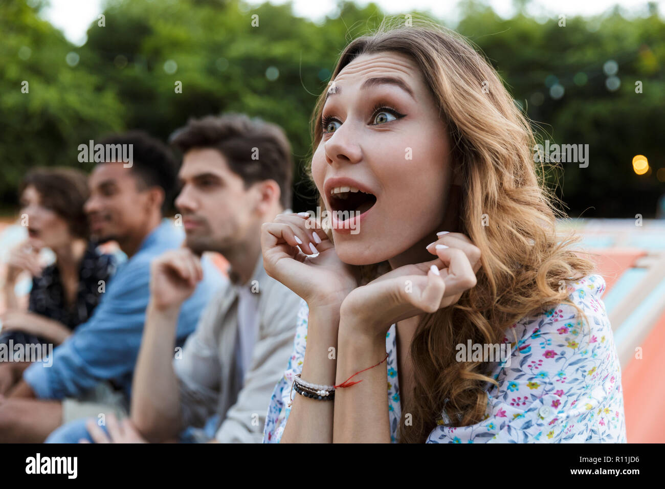Image of shocked emotional young group of friends sitting outdoors ...