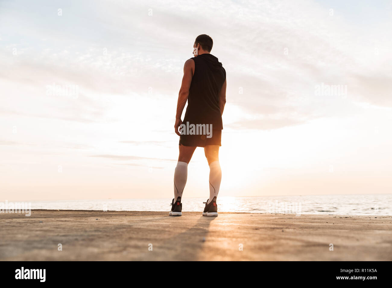 Image of handsome strong young sportsman standing outdoors at the beach ...