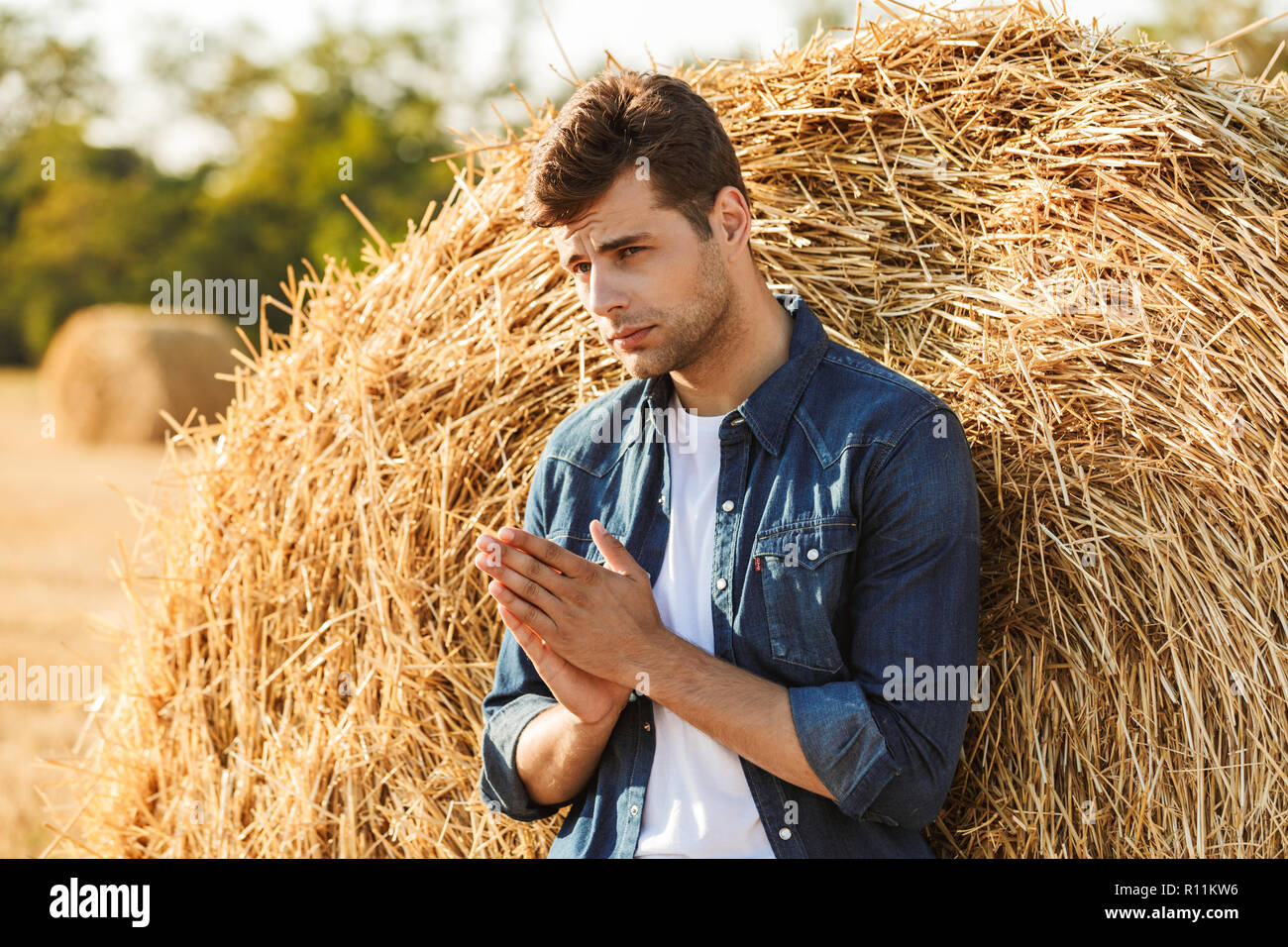Image of young guy 30s walking through golden field and standing near ...