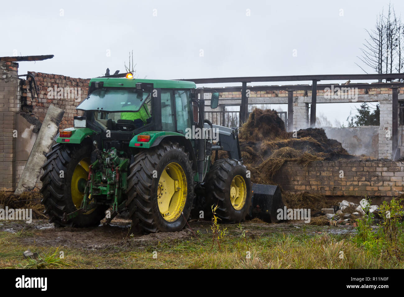 tractor takes hay out of the farm the ruins of a fully burned farm ...