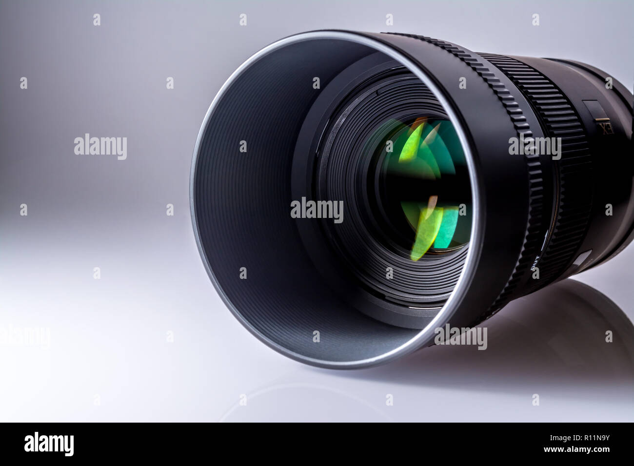 Lens of a SLR camera close-up with a reflection on a grey-white ...