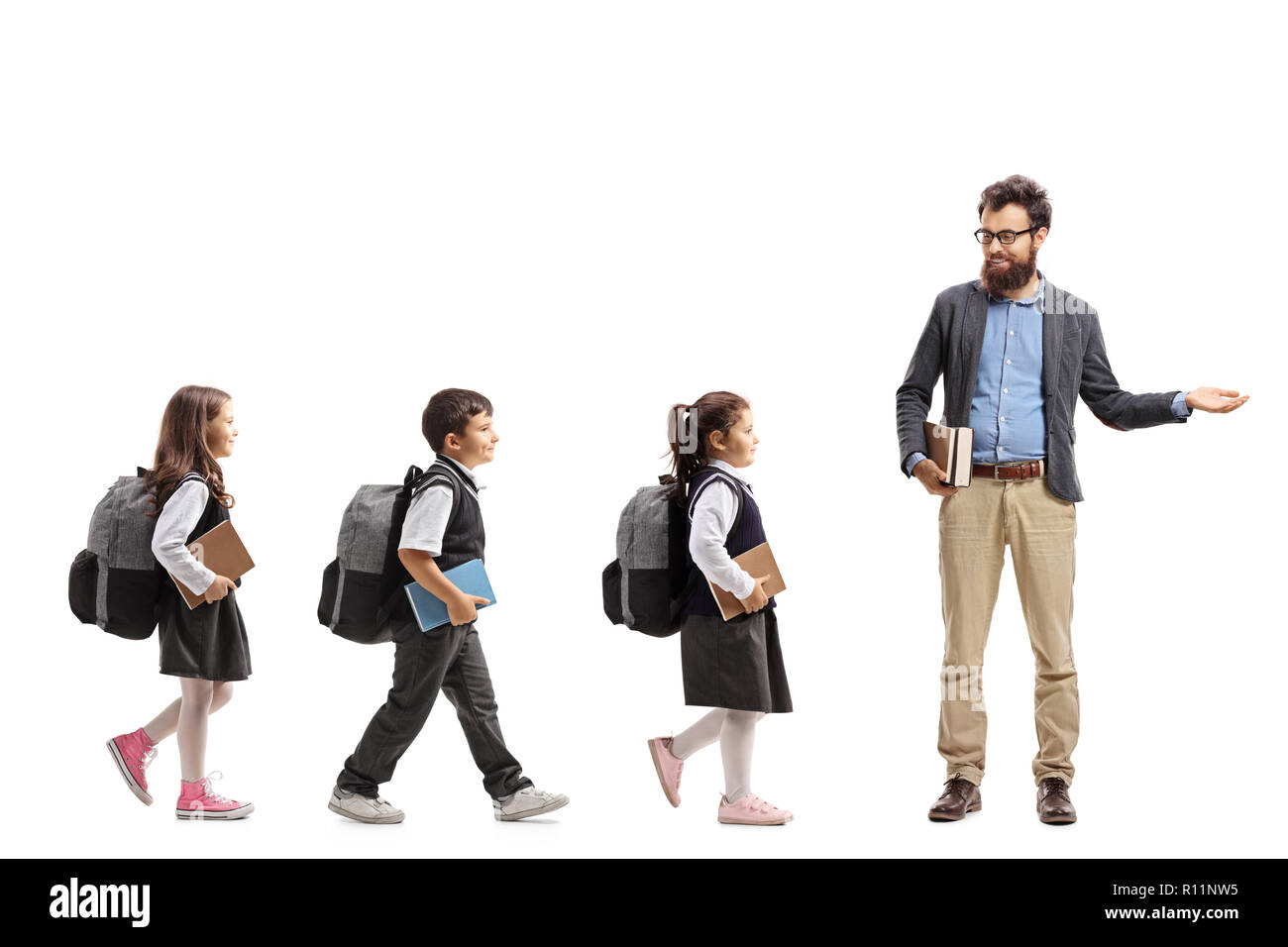 Full length profile shot of schoolchildren walking in a line and a ...
