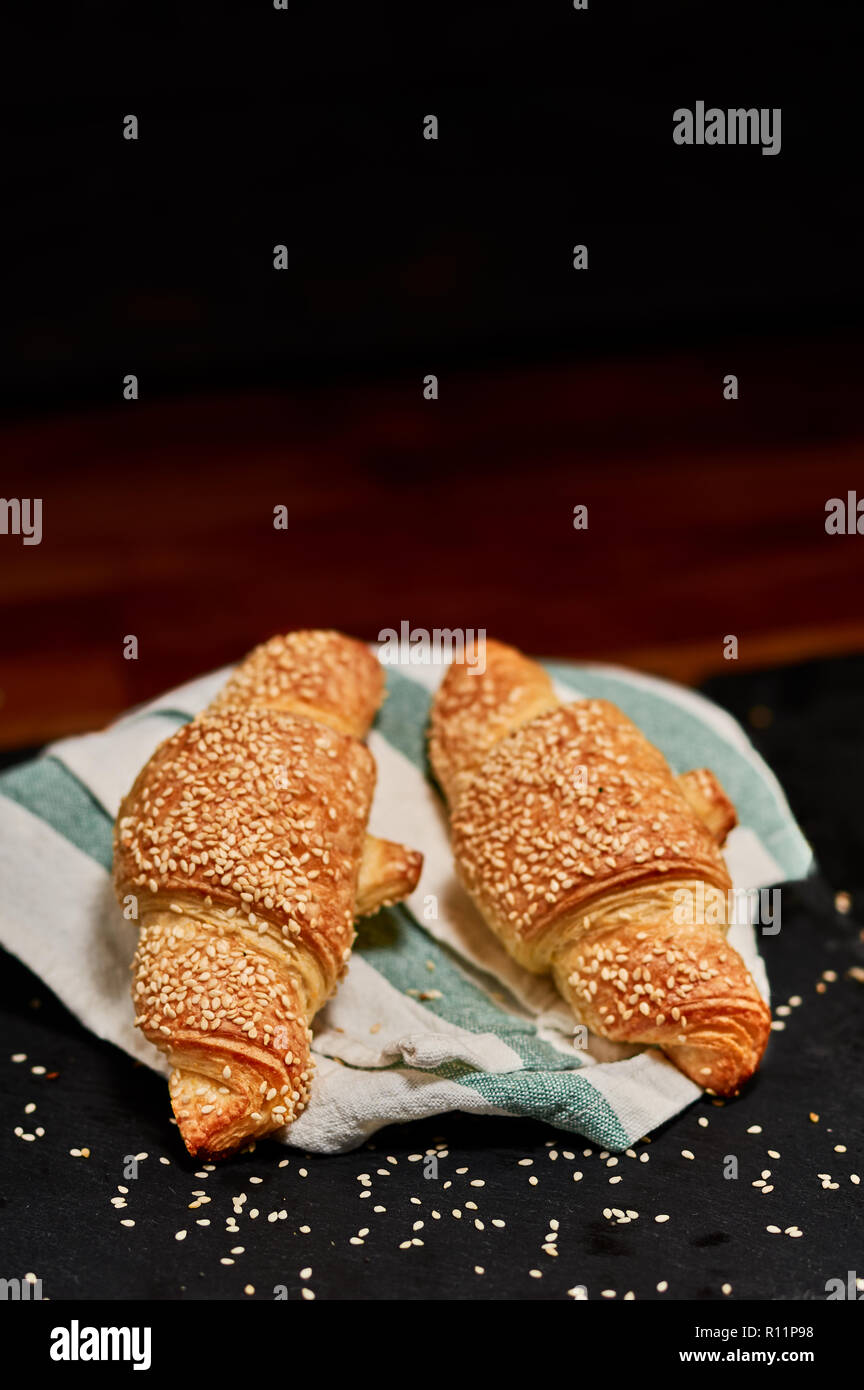 Freshly made rolled puffed pastry with sesame seeds on black stone ...