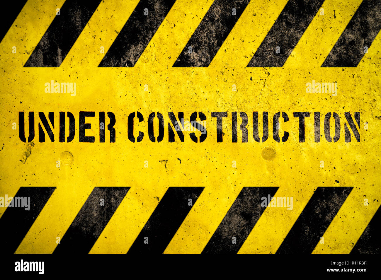 Under construction warning sign text with yellow black stripes painted ...