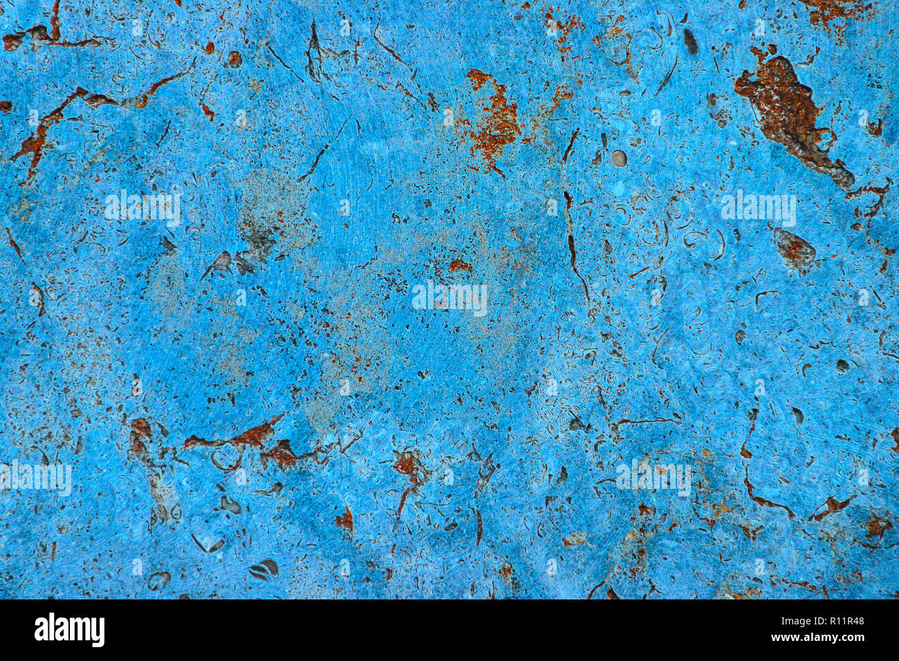 Blue cyan color facade stone wall with imperfections, orange red holes ...