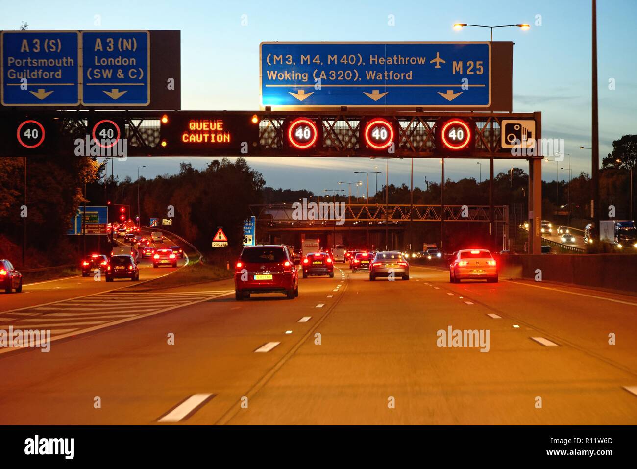 Busy rush hour traffic on the M25 motorway at dusk from a drivers point ...