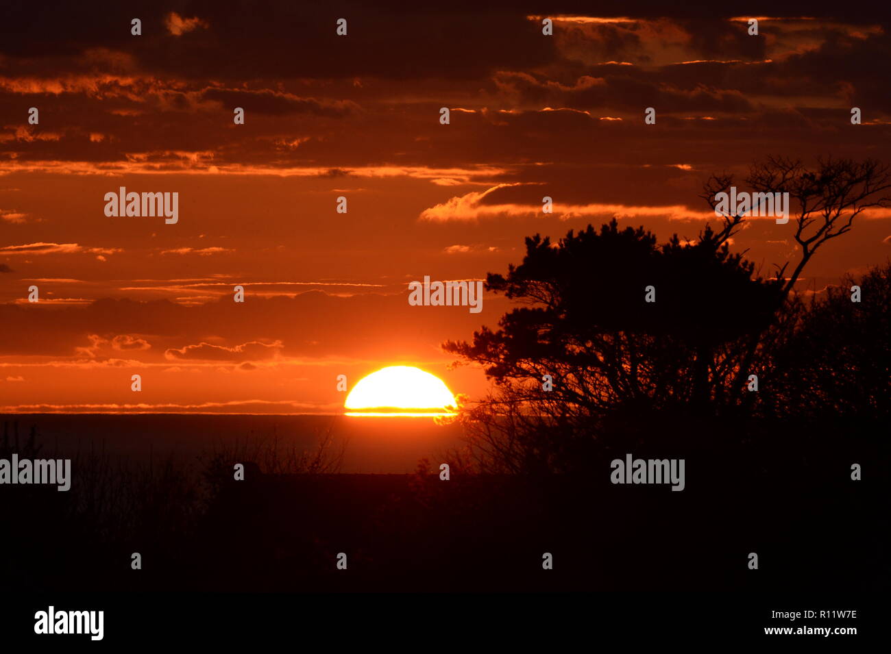 Sunset at Mumbles. A Setting Sun disappears below the horizon causing ...