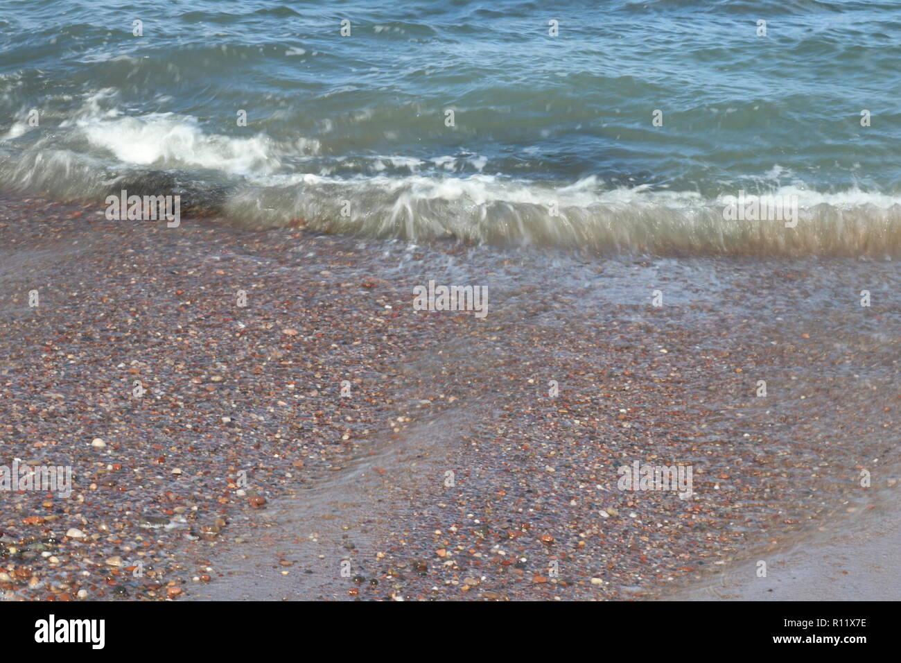 Pebbles on beach with wave arriving Stock Photo - Alamy