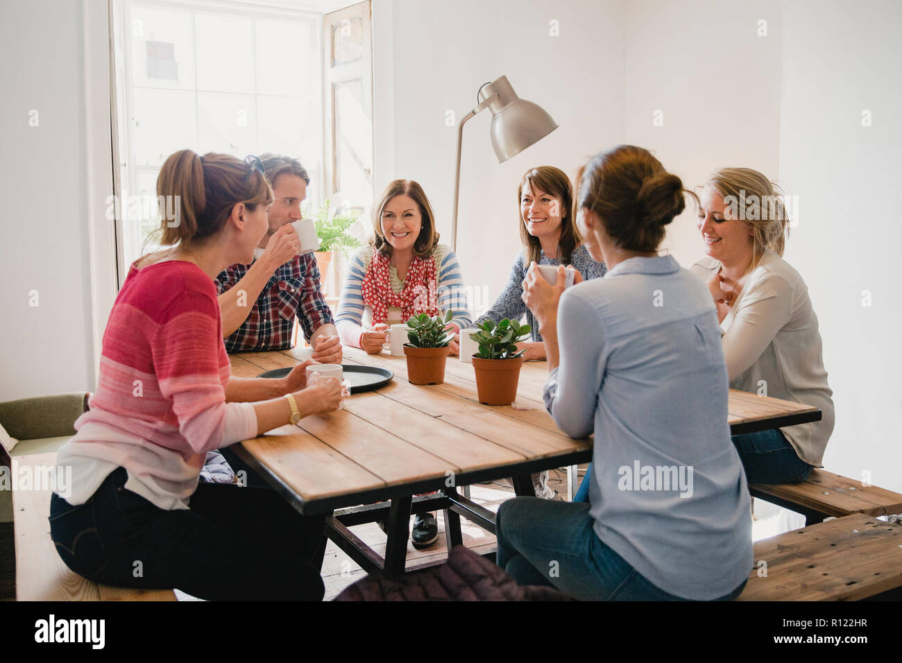 Group of employees at a small coffee shop sitting around a table having ...