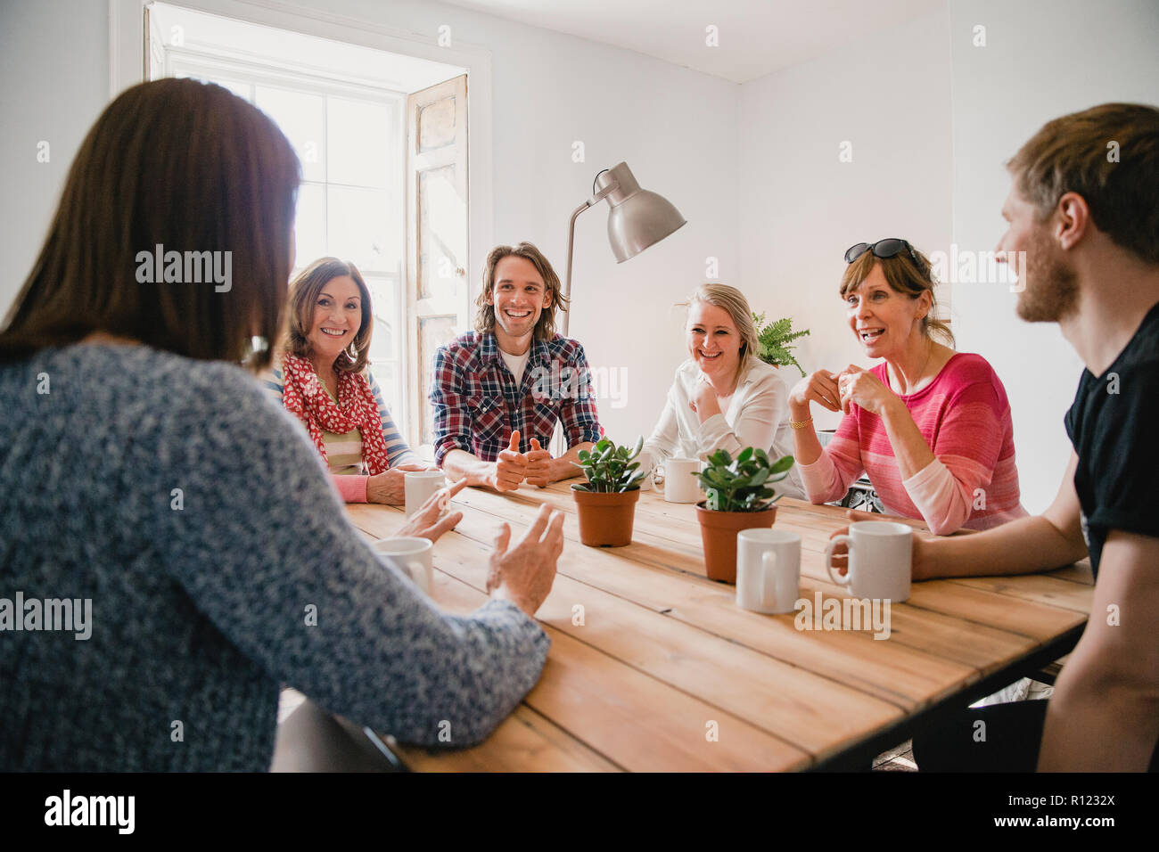 Group of employees at a small coffee shop sitting around a table having ...