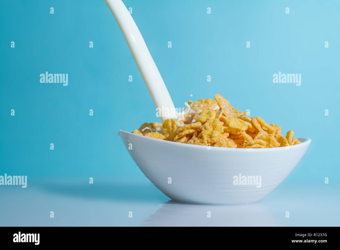 Milk stream jet pouring into a bowl with yellow flakes, milk splashes ...