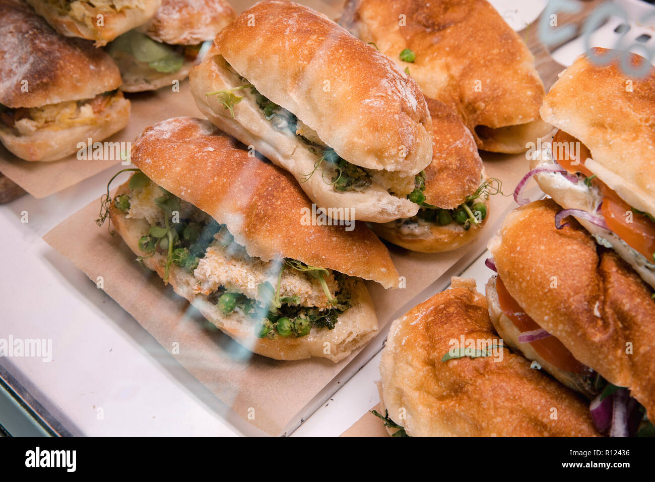 Stack of sandwiches in a coffee shop display cabinet. There is a ...
