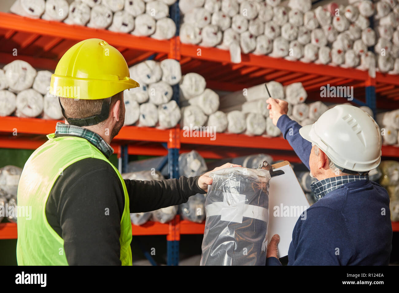 Two warehouse workers work together in the carpet warehouse in a ...