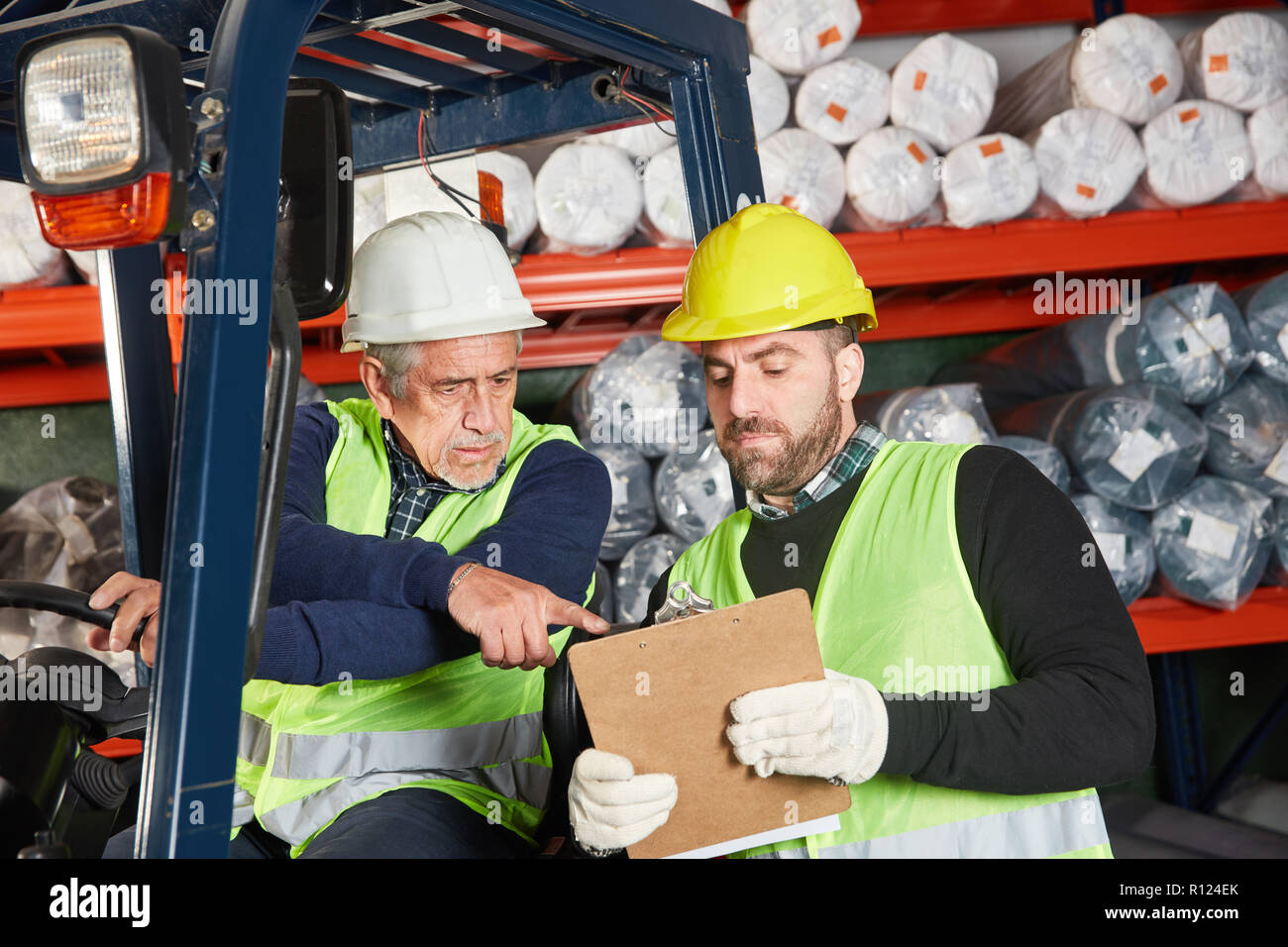 Workers as forklift driver and colleague work together in the warehouse ...