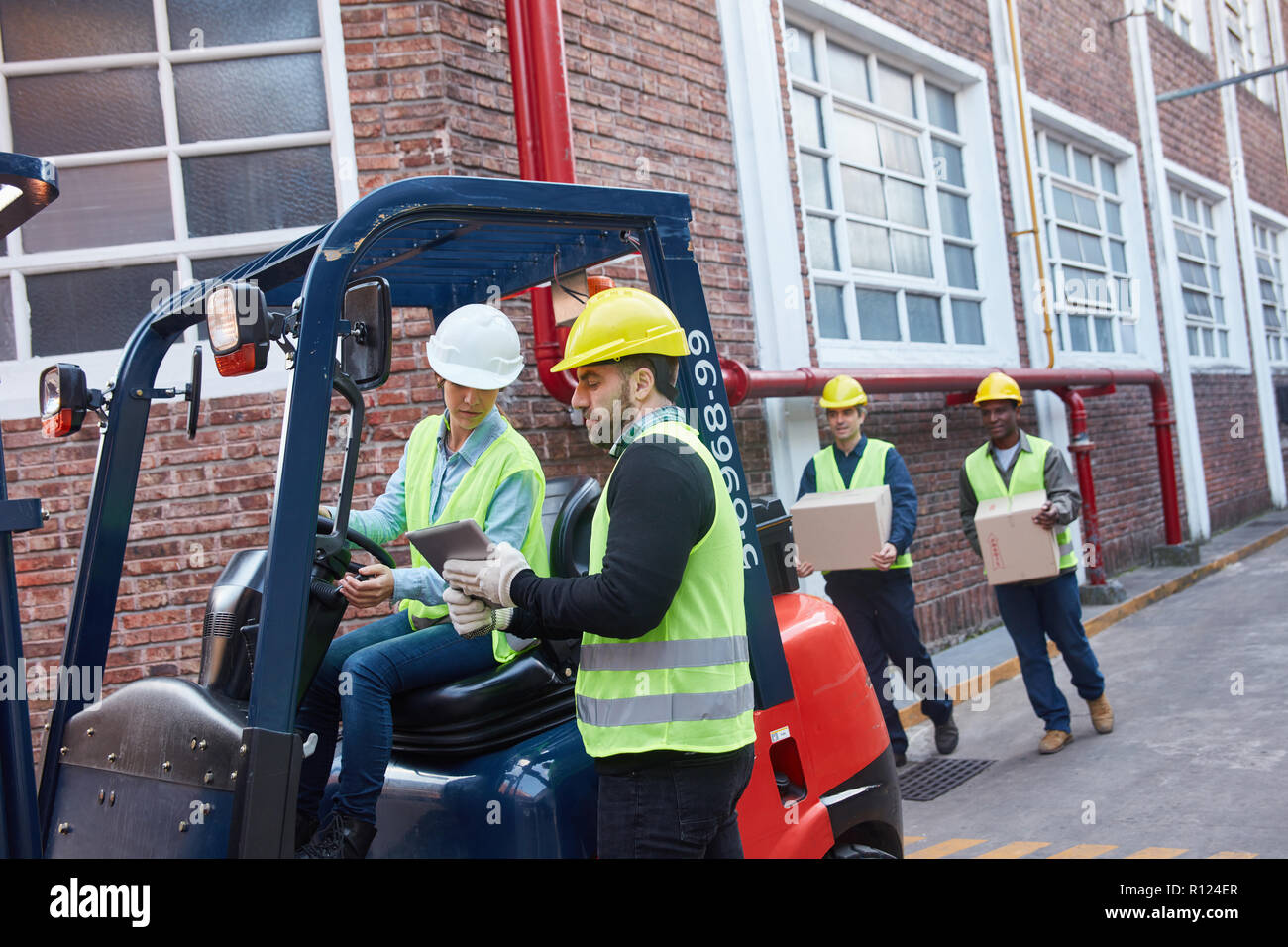 Warehouse workers with parcels and forklift are preparing a delivery ...