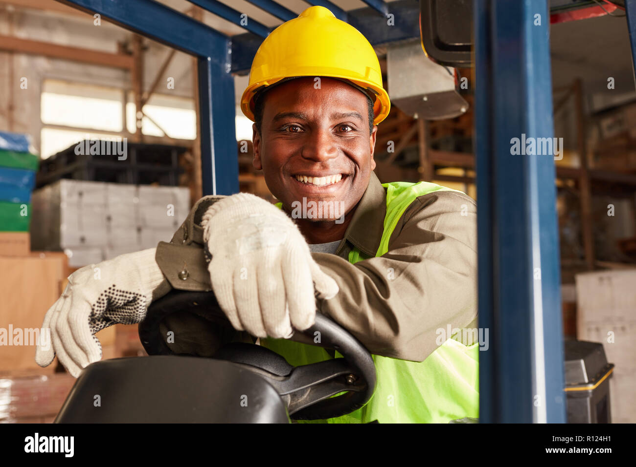 African logistics man as a forklift driver in the warehouse of a ...