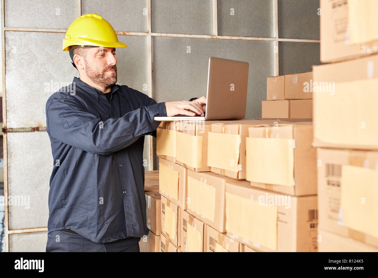 Worker with laptop computer in warehouse prepares package for shipment ...